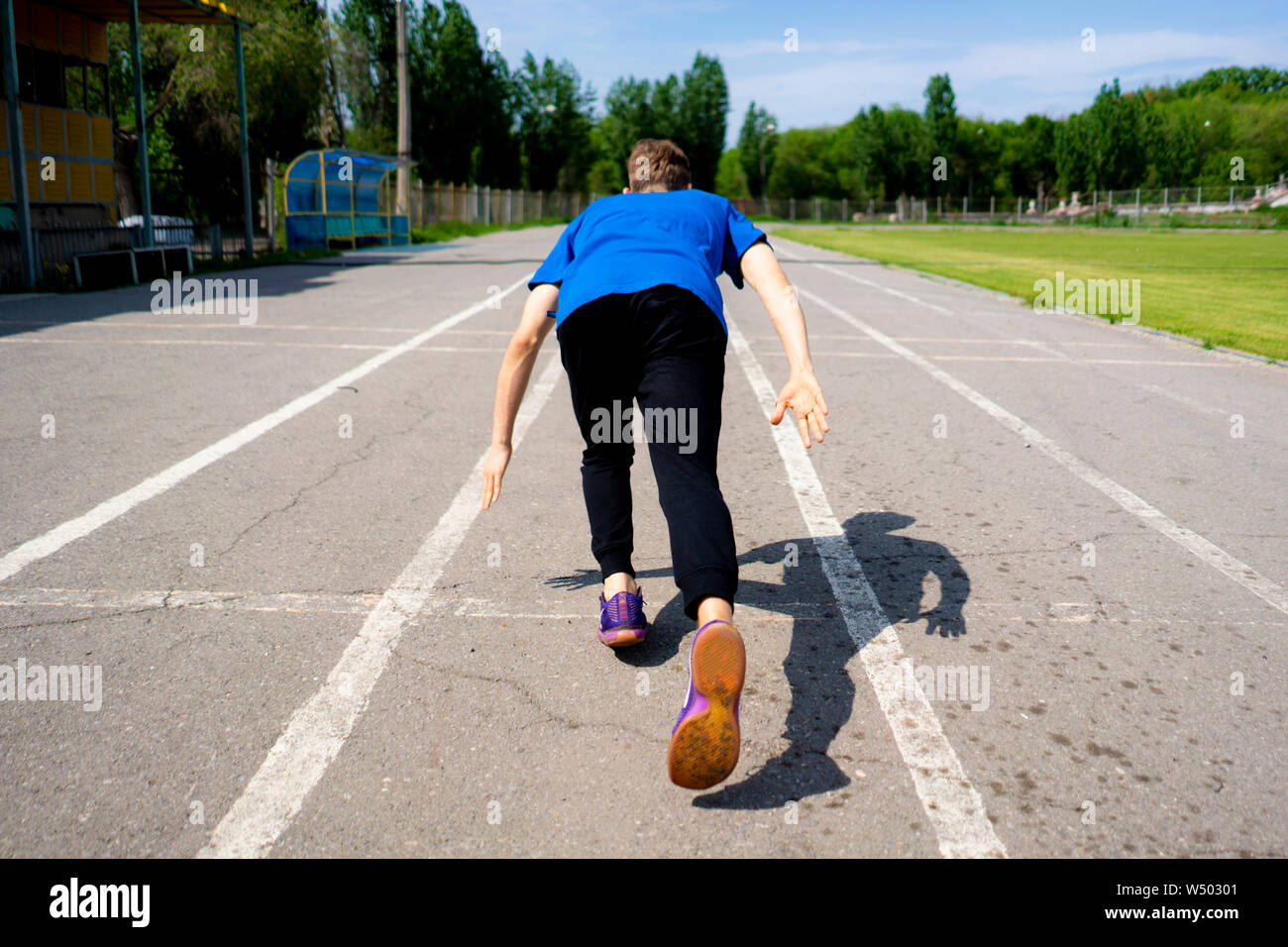 young runner athlete in the low start position on the sports track on ...