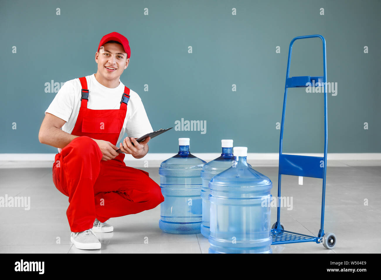 Delivery man with bottles of water indoors Stock Photo - Alamy