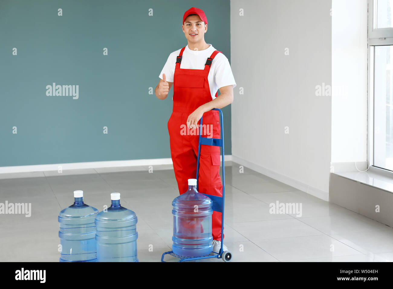 Delivery man with bottles of water indoors Stock Photo - Alamy