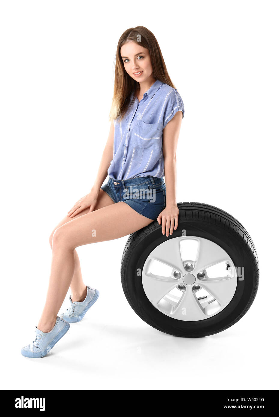 Young woman with car tire on white background Stock Photo - Alamy