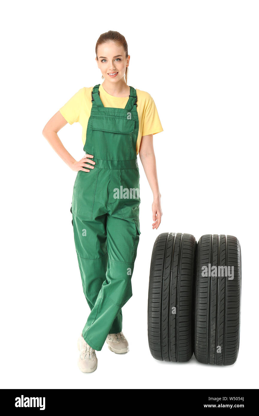 Young female mechanic in uniform with car tires on white background ...