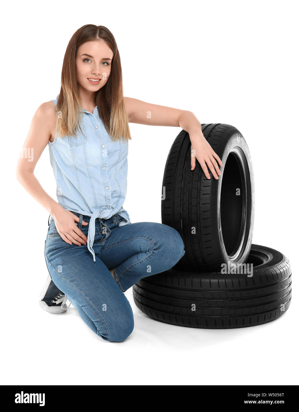 Young woman with car tires on white background Stock Photo - Alamy