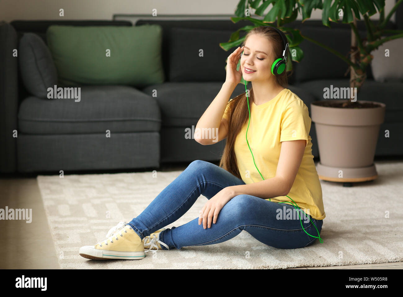 Beautiful young woman listening to music at home Stock Photo - Alamy