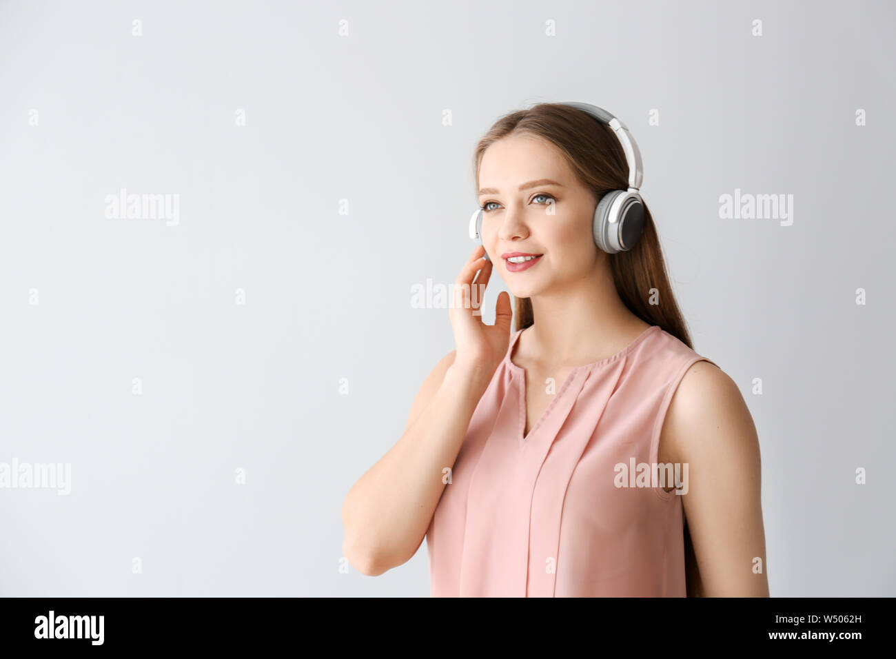 Beautiful young woman listening to music on light background Stock ...