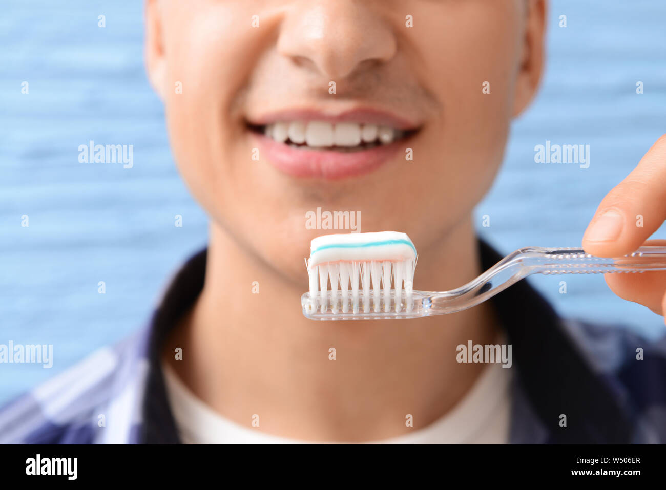 Handsome man with toothbrush and paste on color background, closeup ...