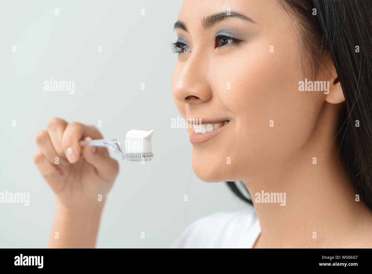 Beautiful Asian Woman With Toothbrush And Paste On Light Background