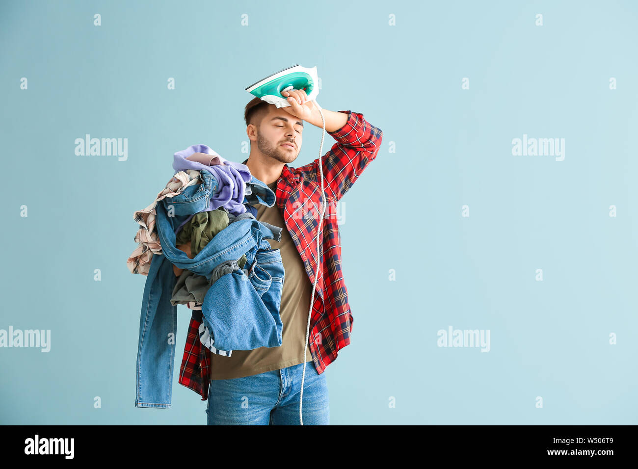 Stressed young man with iron and clothes on grey background Stock Photo ...