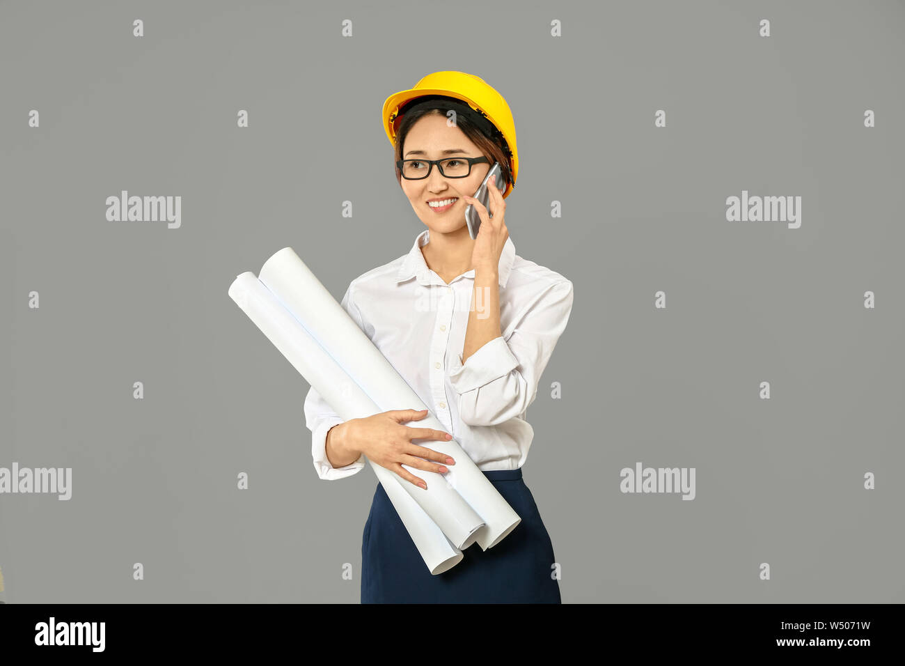 Female Asian engineer talking by phone on grey background Stock Photo ...