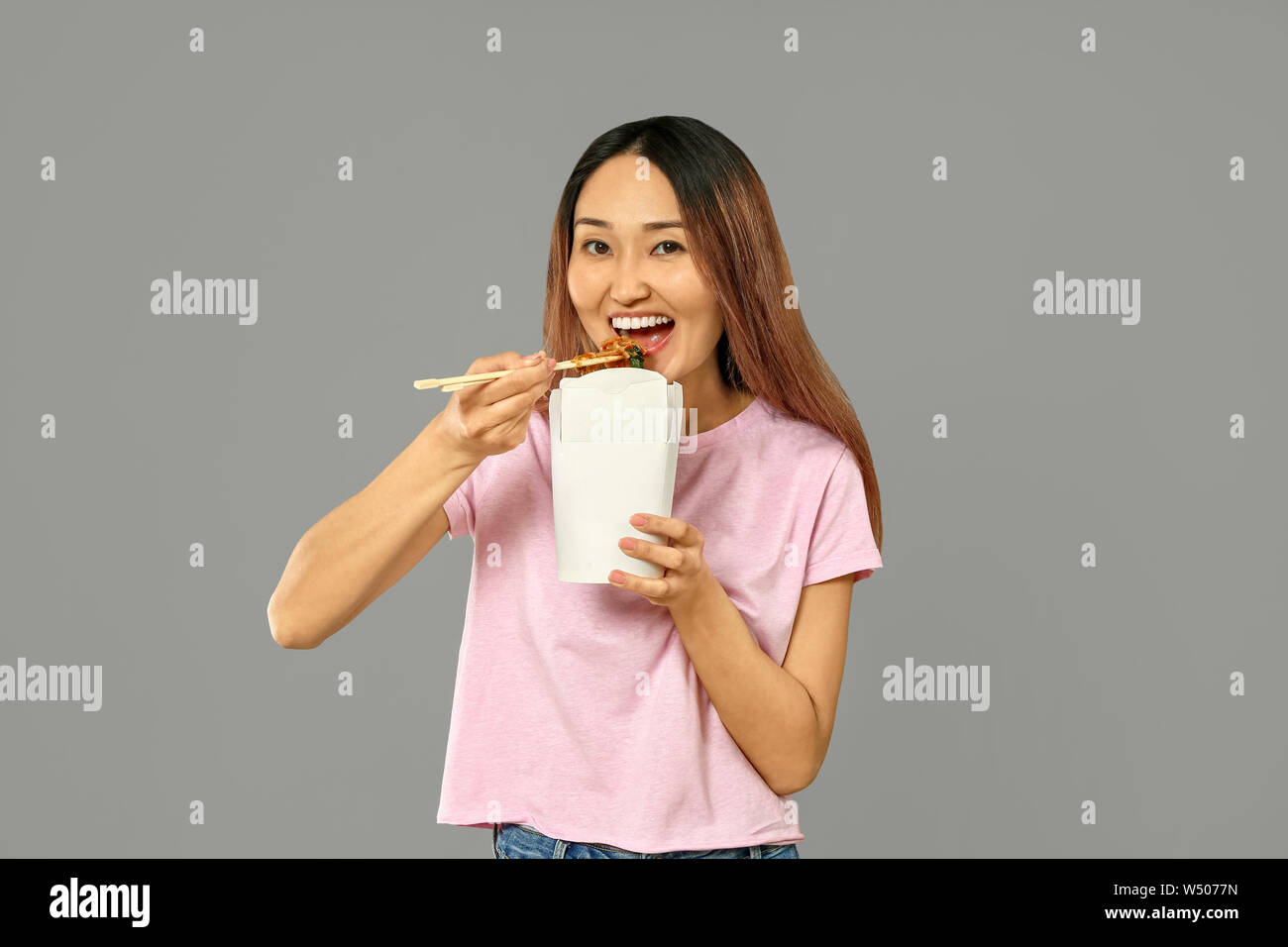 Asian woman eating Chinese food on grey background Stock Photo - Alamy