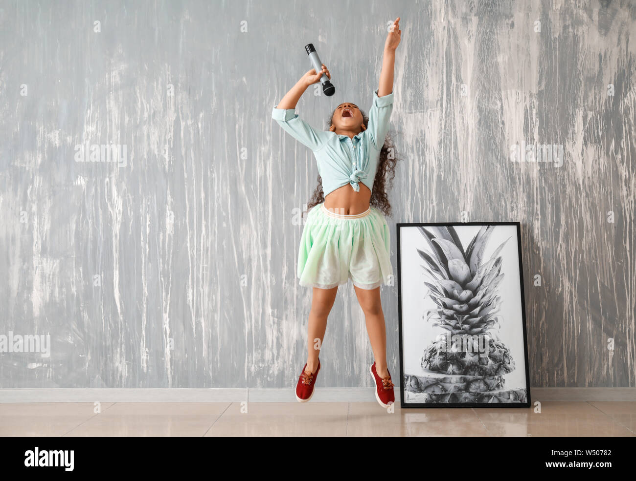 Little African-American singer against grunge wall Stock Photo - Alamy