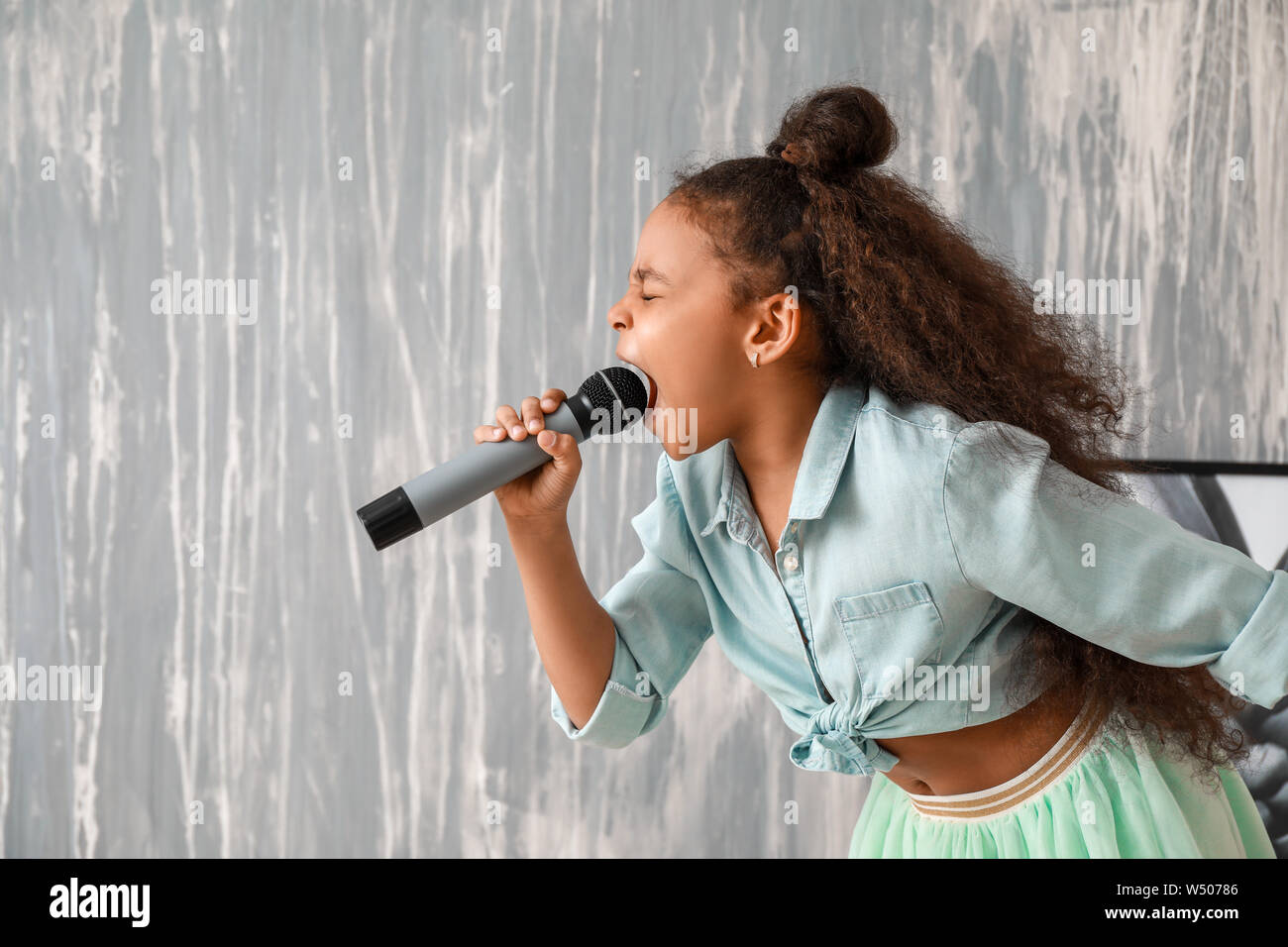 Little African-American singer against grunge wall Stock Photo - Alamy