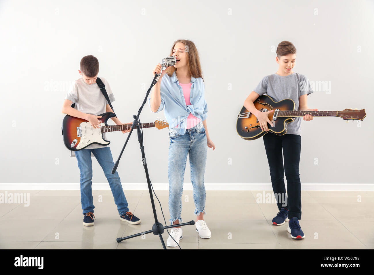 Teenage musicians playing against light wall Stock Photo - Alamy