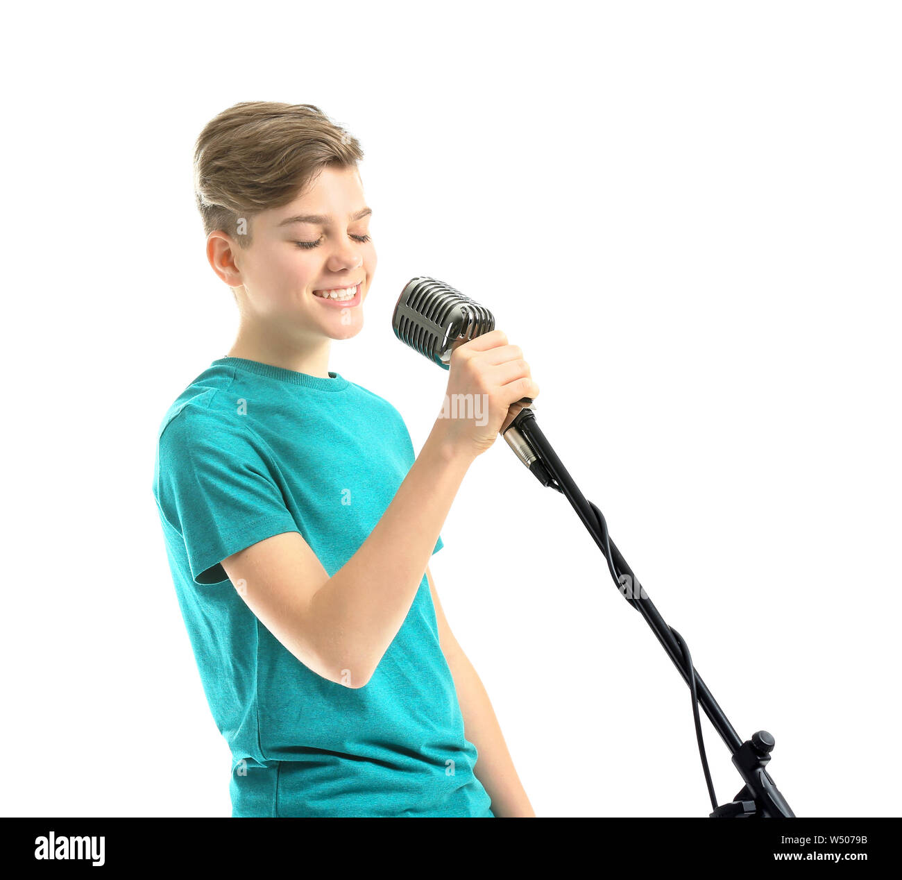 Teenage boy with microphone singing against white background Stock ...