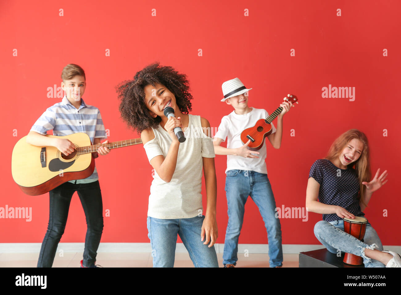 Teenage musicians playing against color wall Stock Photo - Alamy
