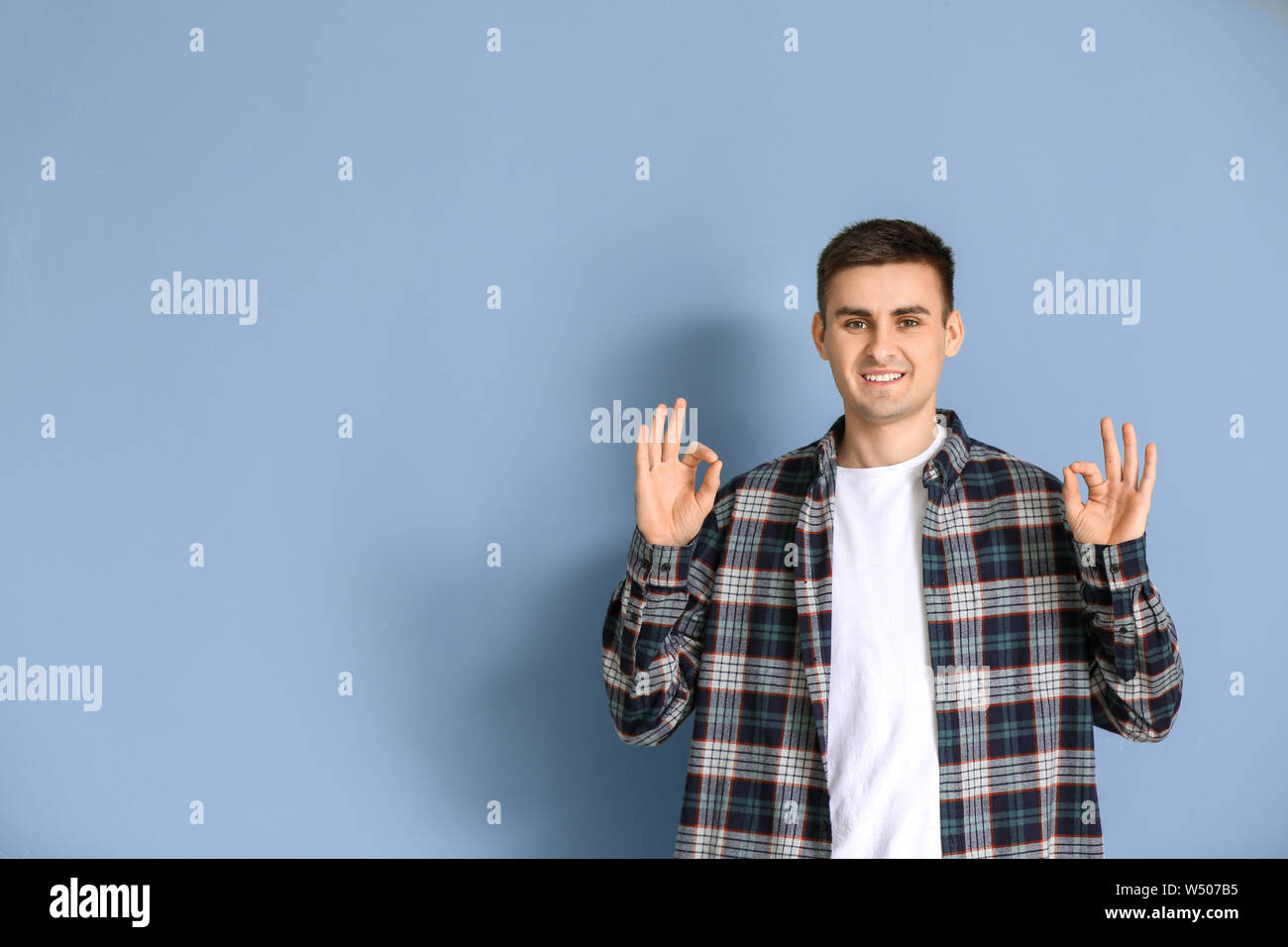 Young deaf mute man using sign language on grey background Stock Photo ...