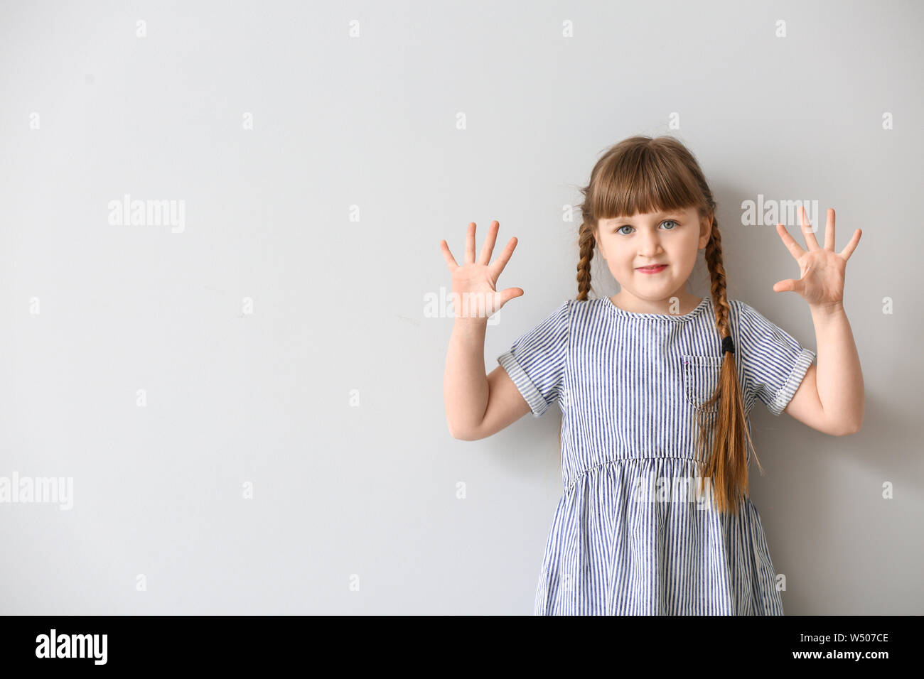 Cute deaf mute girl using sign language on light background Stock Photo ...