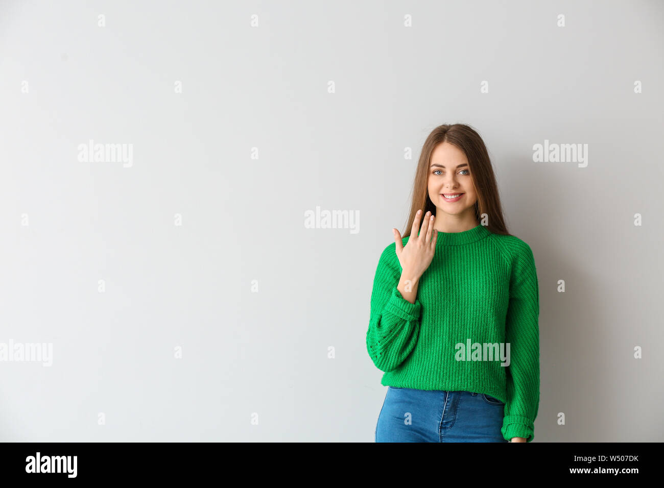 Young deaf mute woman using sign language on light background Stock ...