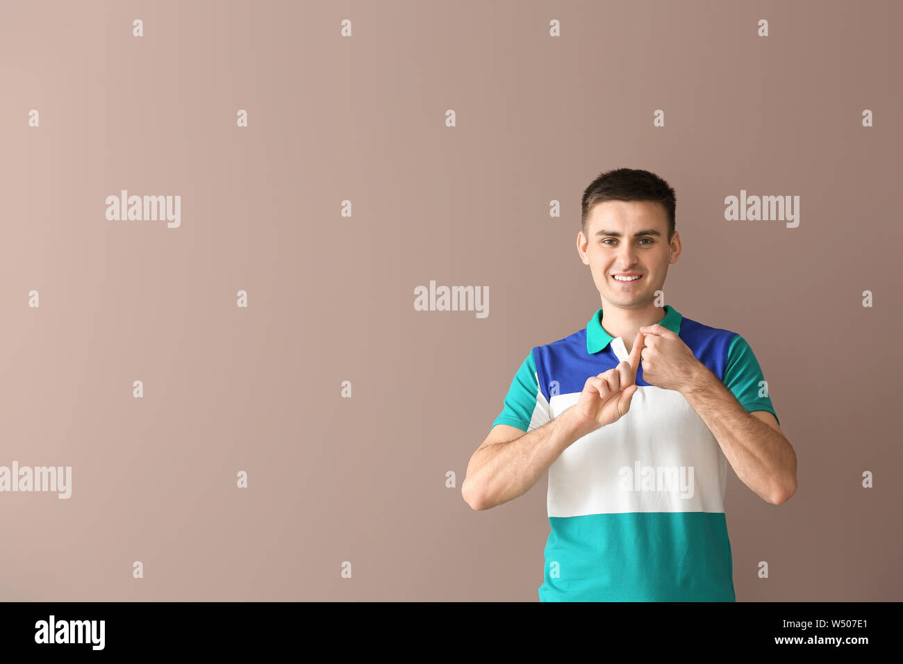 Young deaf mute man using sign language on color background Stock Photo ...