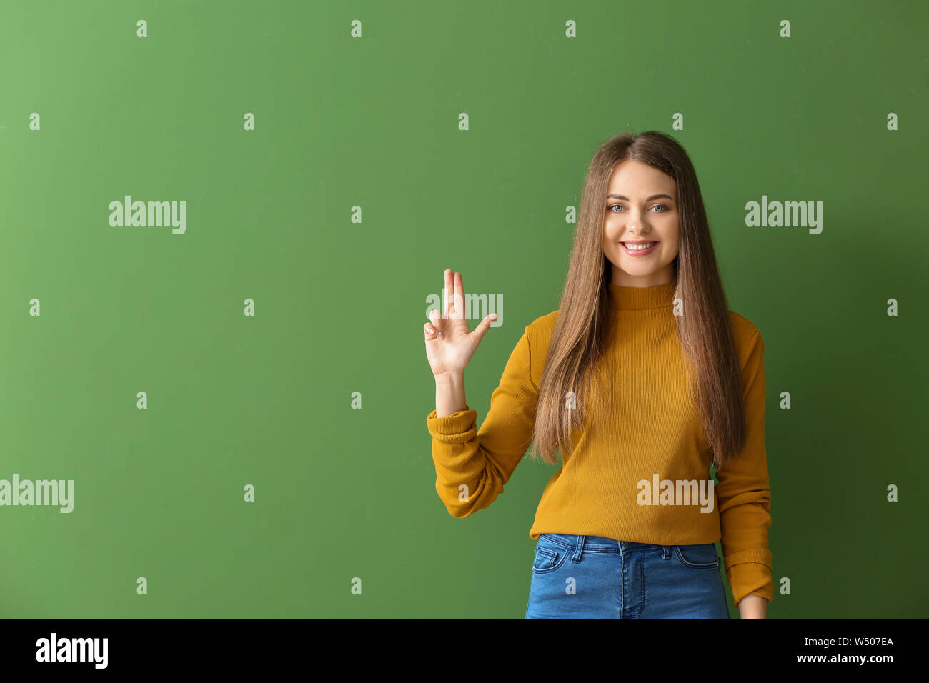 Young deaf mute woman using sign language on color background Stock ...