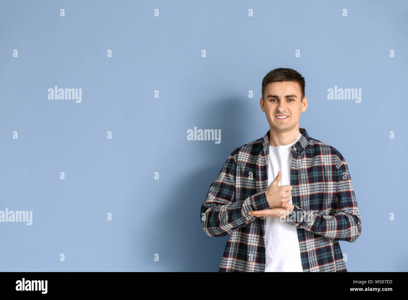 Young deaf mute man using sign language on grey background Stock Photo ...