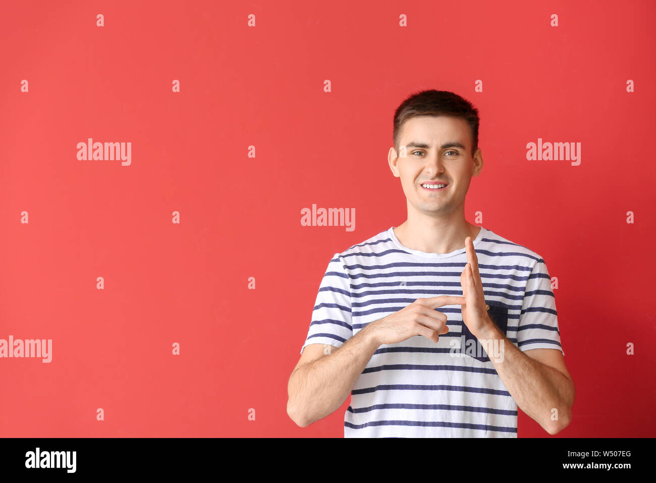 Young deaf mute man using sign language on color background Stock Photo ...