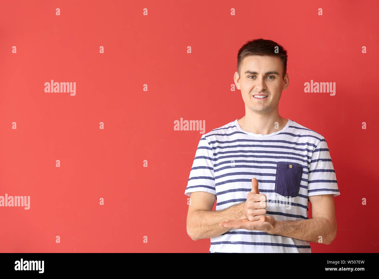 Young deaf mute man using sign language on color background Stock Photo ...