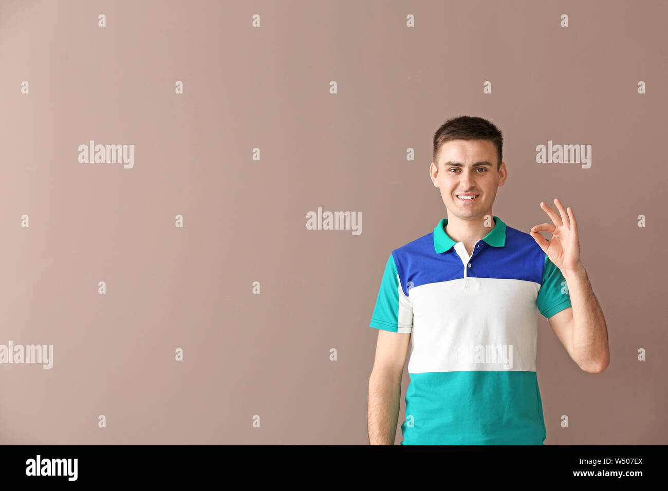 Young deaf mute man using sign language on color background Stock Photo ...