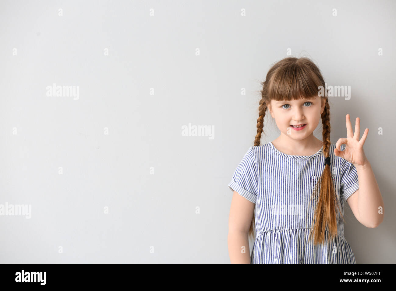 Cute deaf mute girl using sign language on light background Stock Photo ...