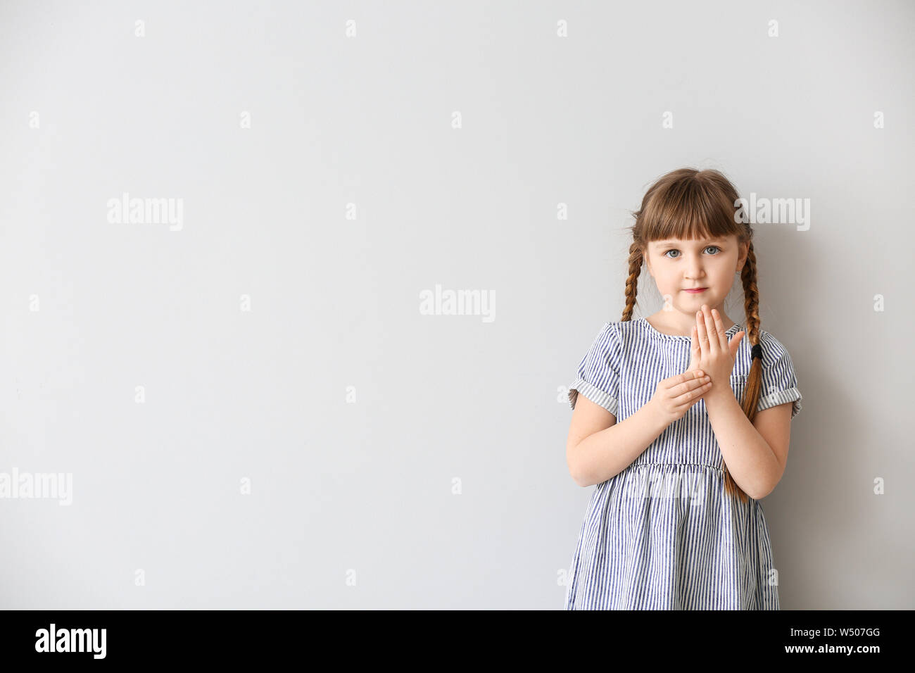 Cute deaf mute girl using sign language on light background Stock Photo ...