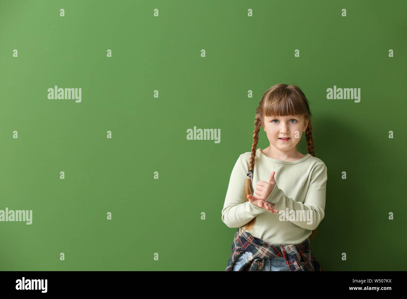 Cute deaf mute girl using sign language on color background Stock Photo ...