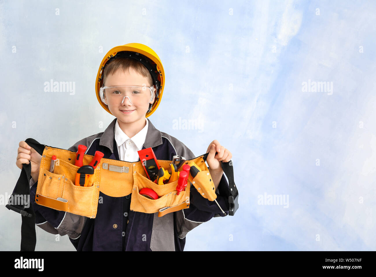 Cute little boy with tools belt on color background Stock Photo - Alamy