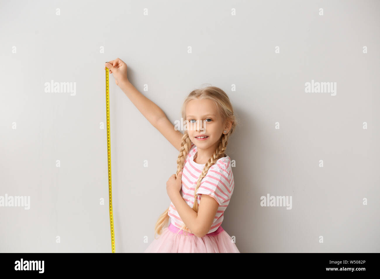 Cute little girl measuring height near wall Stock Photo - Alamy