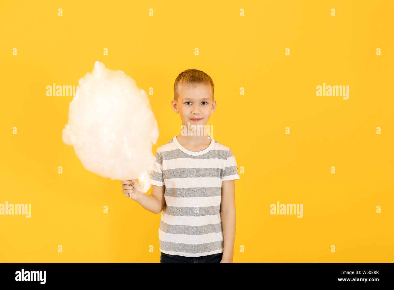 Cute little boy with cotton candy on color background Stock Photo - Alamy