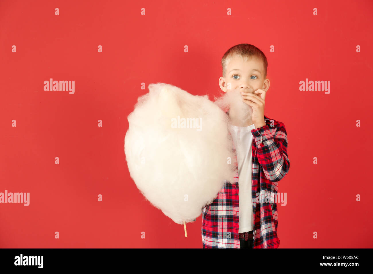 Cute little boy with cotton candy on color background Stock Photo - Alamy