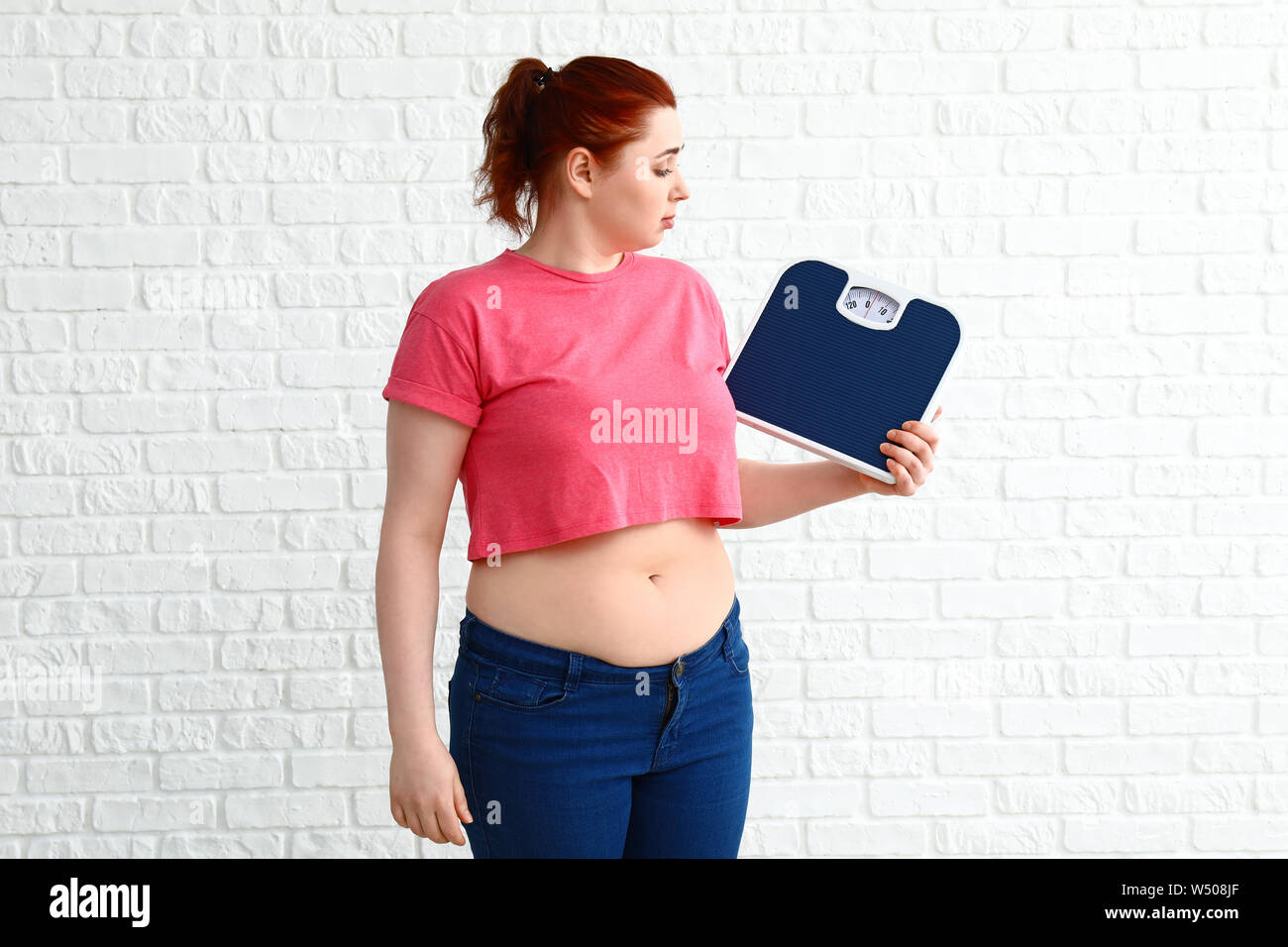 Overweight woman with scales on white background. Weight loss concept ...
