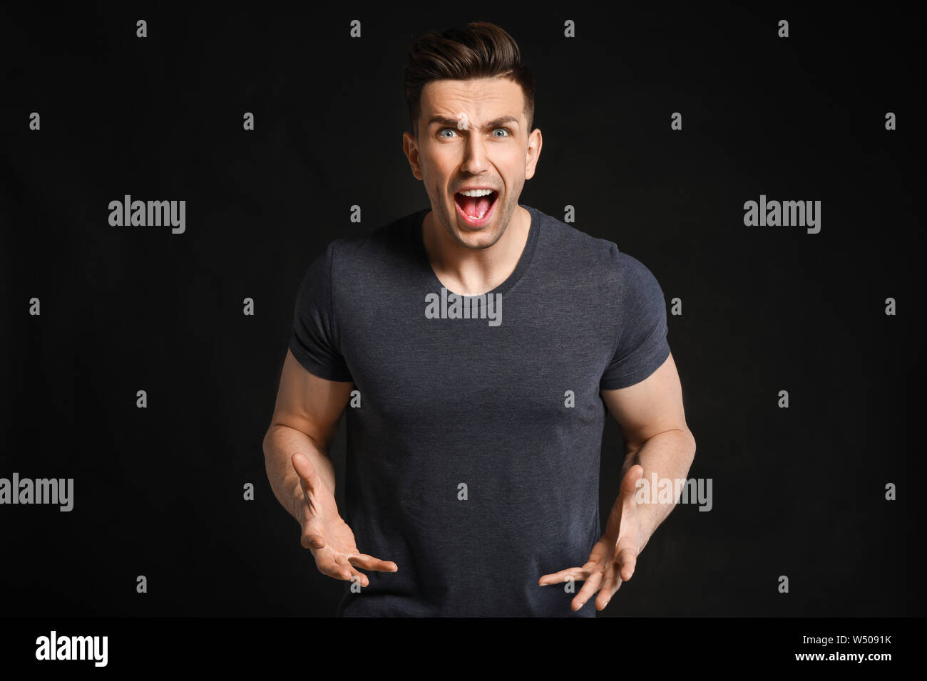 Aggressive young man on dark background Stock Photo - Alamy