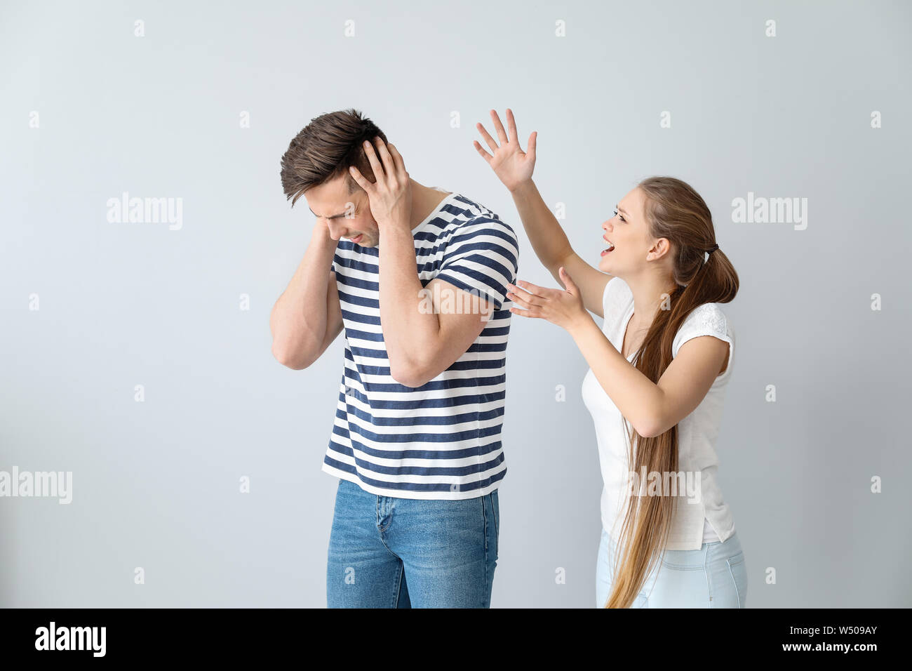 Young quarrelling couple on light background Stock Photo - Alamy