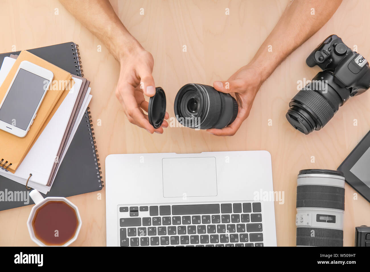 Male photographer with modern equipment and laptop at table, top view ...