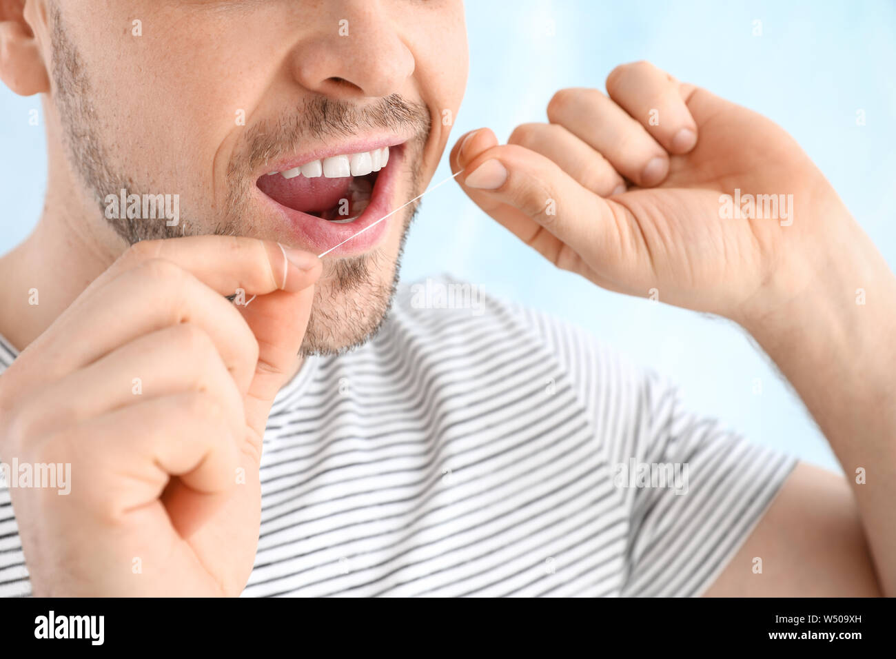 Man flossing teeth on light background, closeup Stock Photo - Alamy