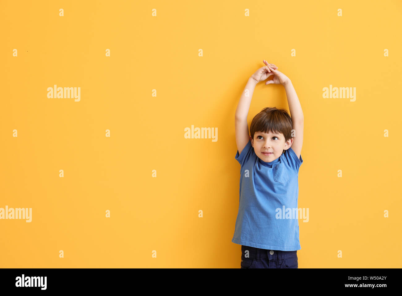 Cute little boy measuring height near color wall Stock Photo - Alamy