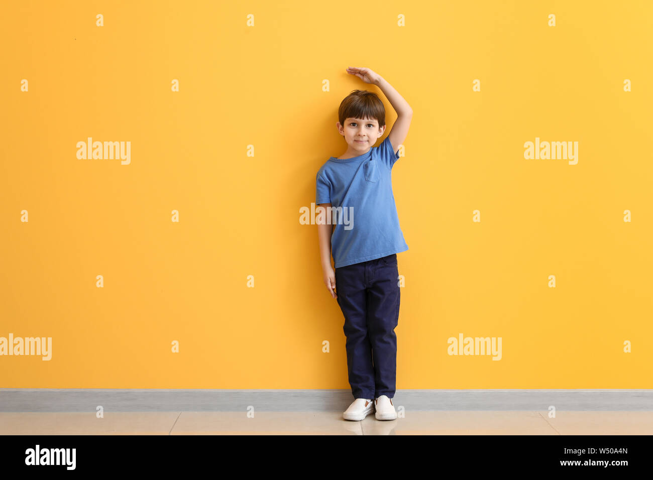 Cute little boy measuring height near color wall Stock Photo - Alamy