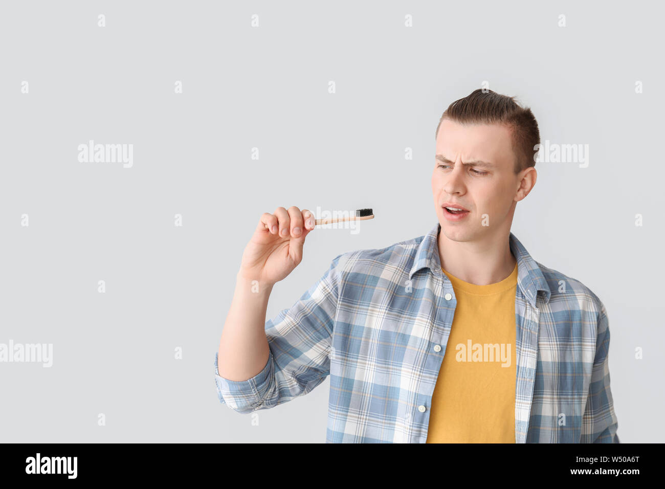 Displeased man with toothbrush on light background Stock Photo - Alamy