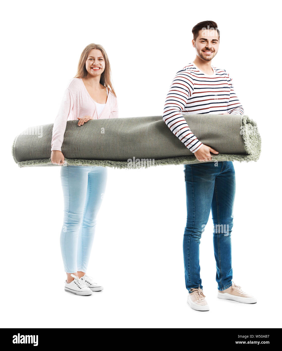 Young couple holding rolled carpet against white background Stock Photo ...