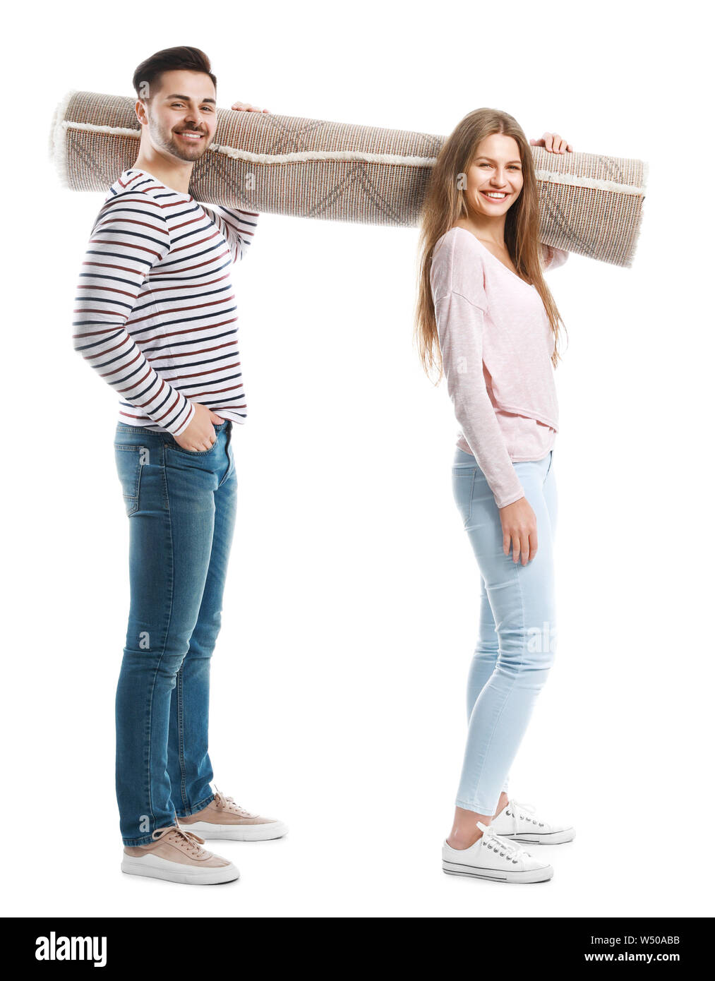 Young couple holding rolled carpet against white background Stock Photo ...