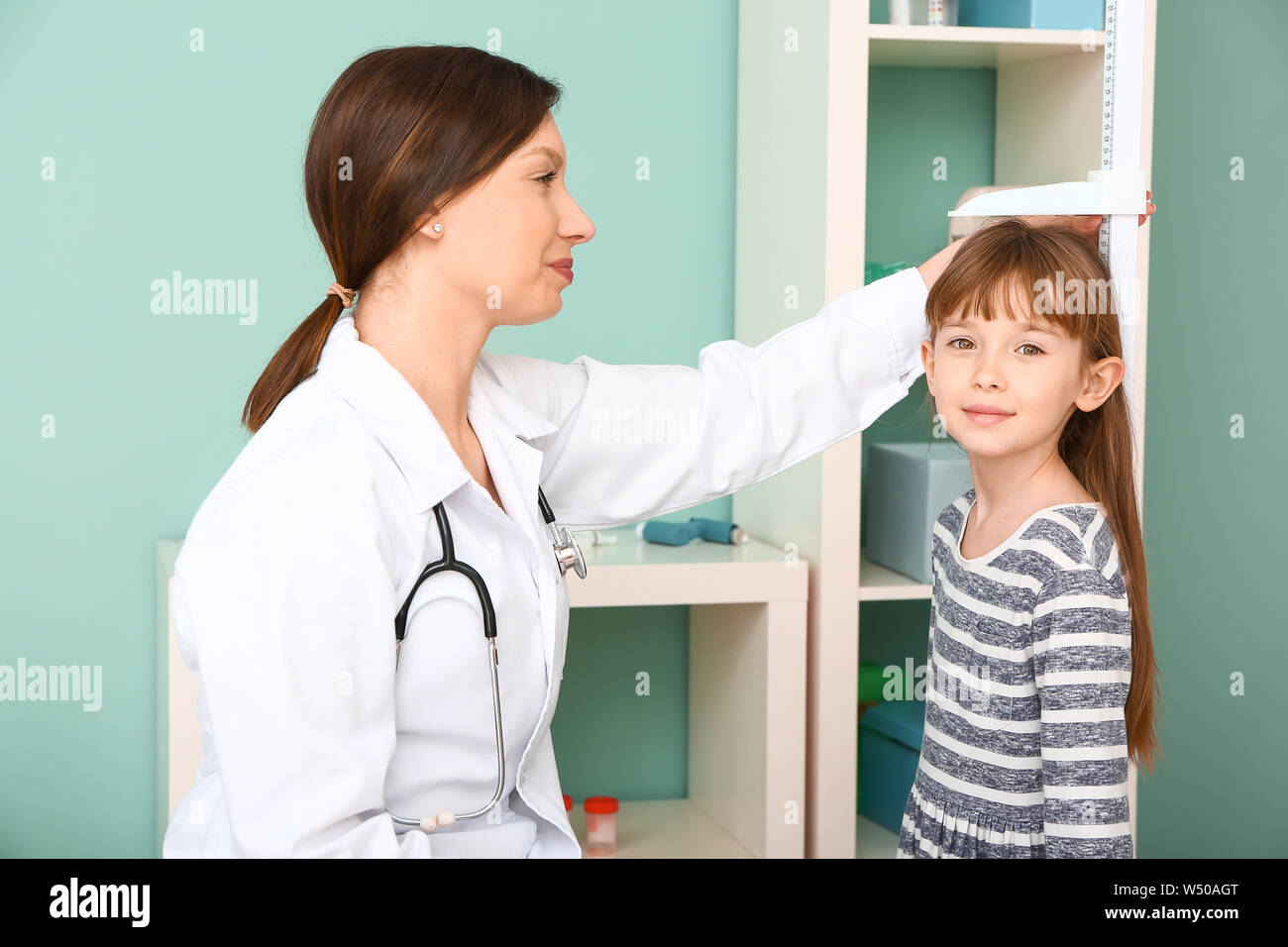 Female doctor measuring height of little girl in hospital Stock Photo ...