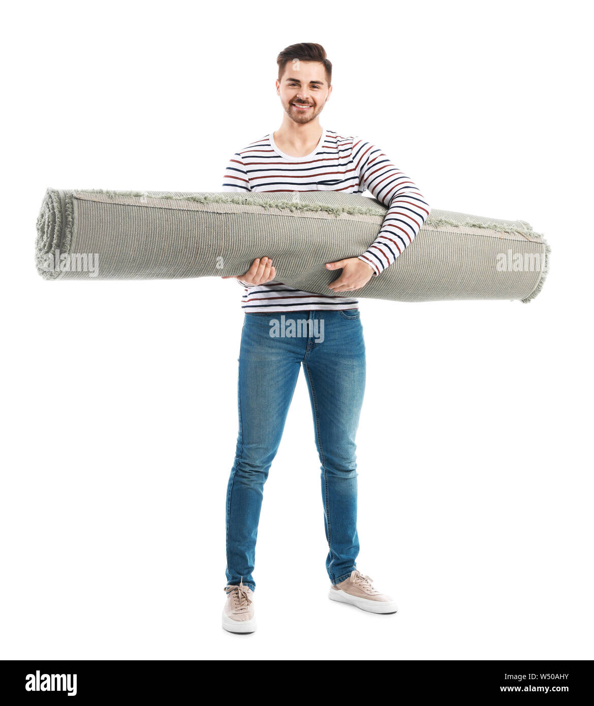 Young man holding rolled carpet against white background Stock Photo ...