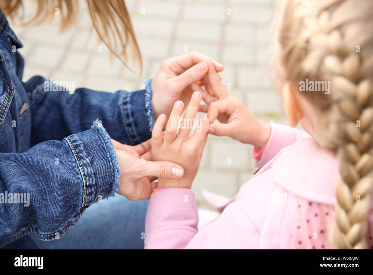 Mother teaching her deaf mute daughter to use sign language outdoors ...