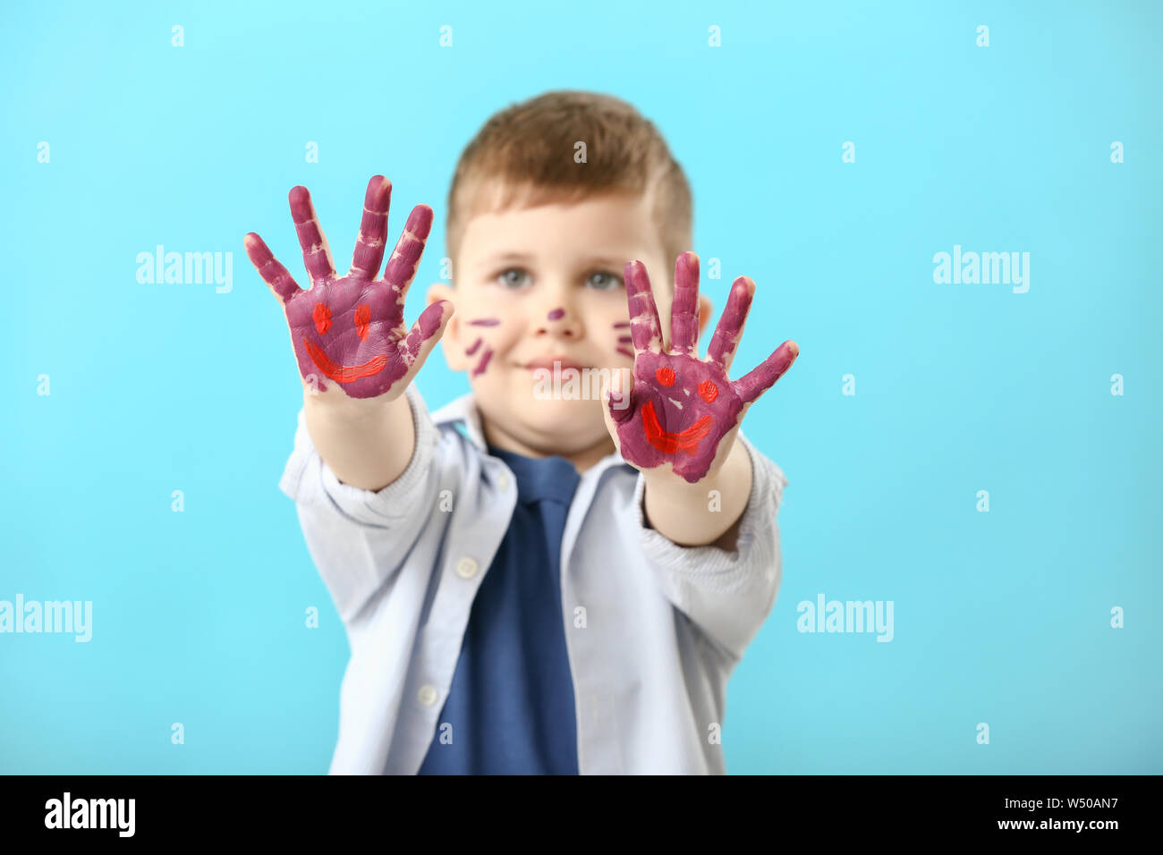 Funny little boy with hands and face in paint on color background Stock ...