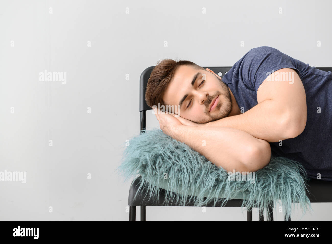 Handsome man sleeping on chairs against grey background Stock Photo - Alamy
