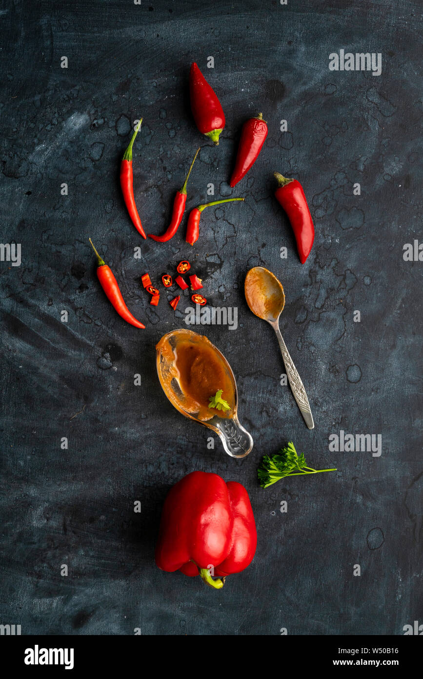 top view of red spicy pepper sauce in a bowl and ingredients for ...